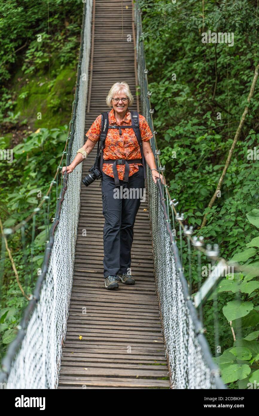 A tourist crosses a swinging bridge in the rainforest of the Atitlan ...