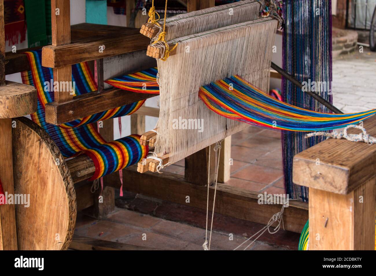 Colorful fabric being woven on a traditional wooden foot-treadle loom ...