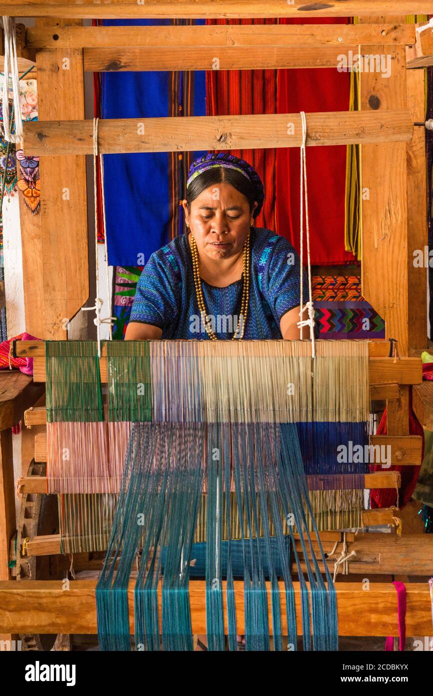 A Mayan woman, wearing typical traditional dress, weaves fabric on a ...