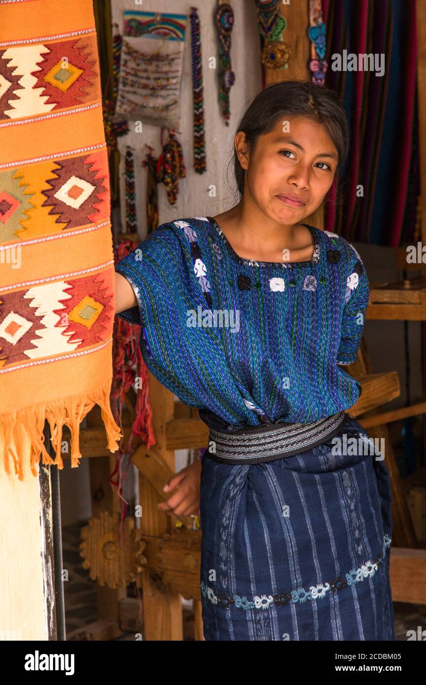 An attractive young Mayan girl wearing typical dress looks out the door ...