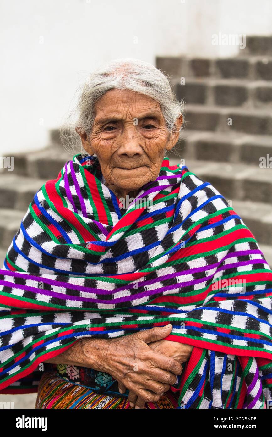 An elderly Mayan woman in traditional dress on the steps of the church ...