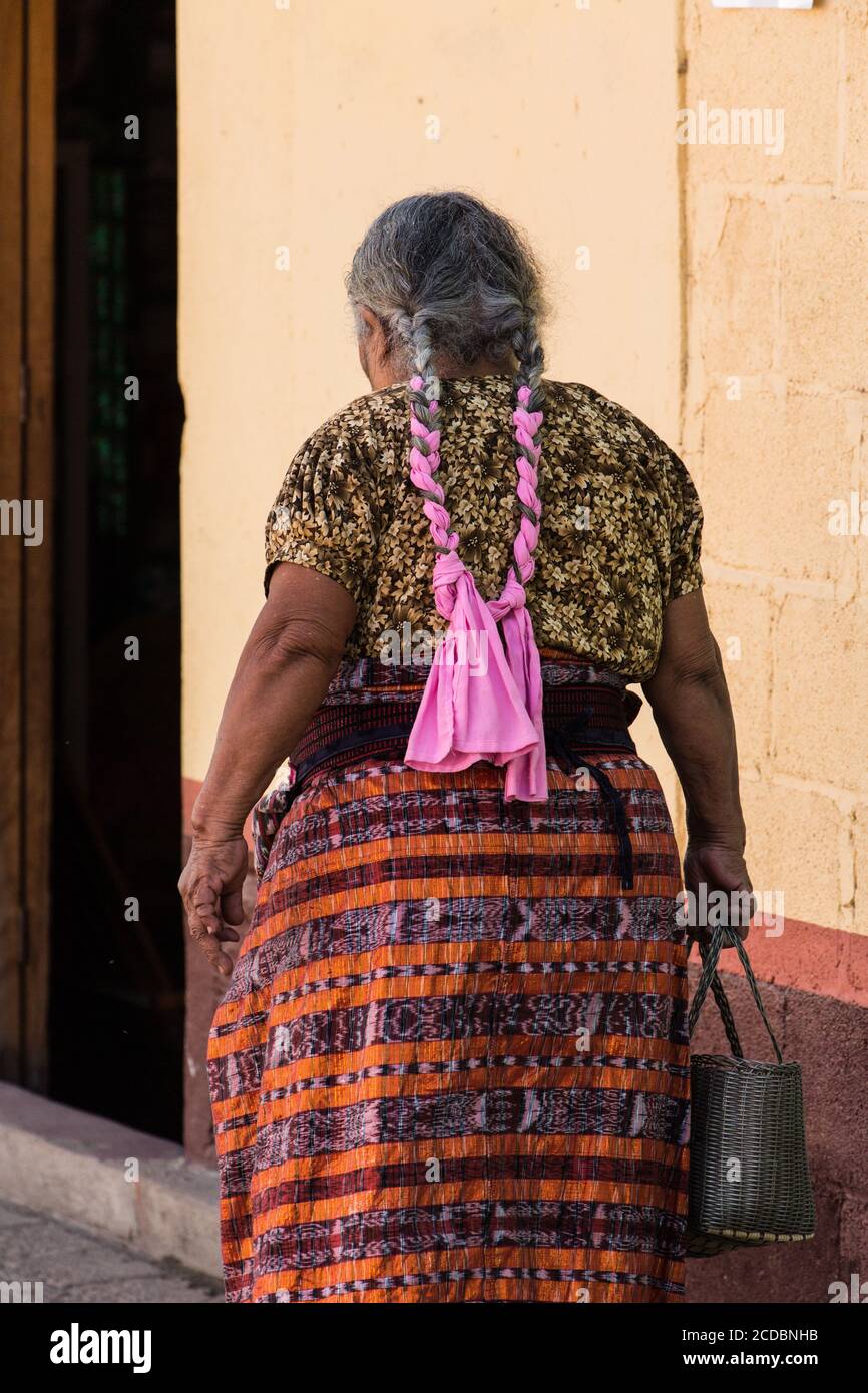 An older Mayan woman wiith ribbons intertwinedd with her braided hair ...