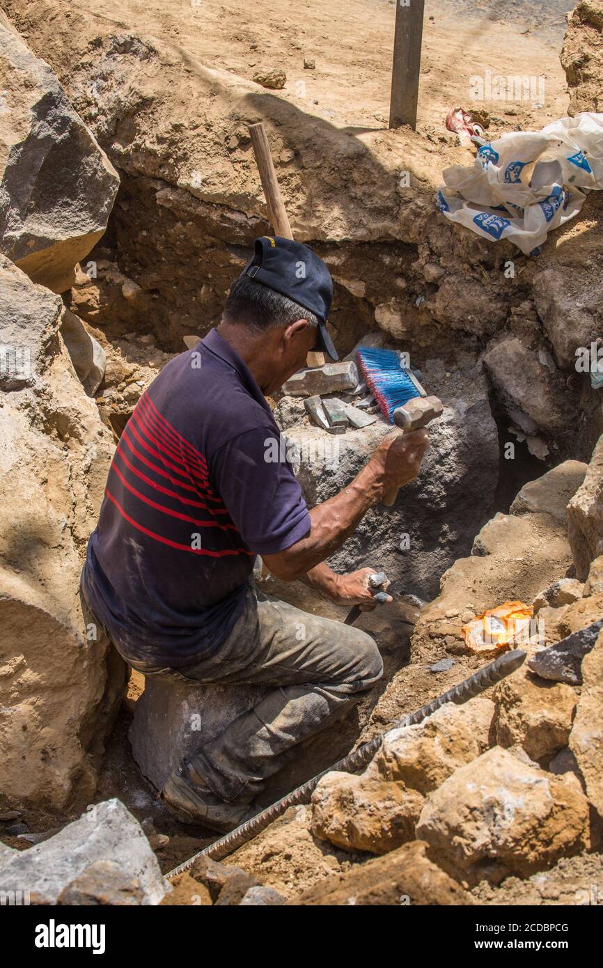 A construction worker breaks rocks with a hammer and chisel in San ...