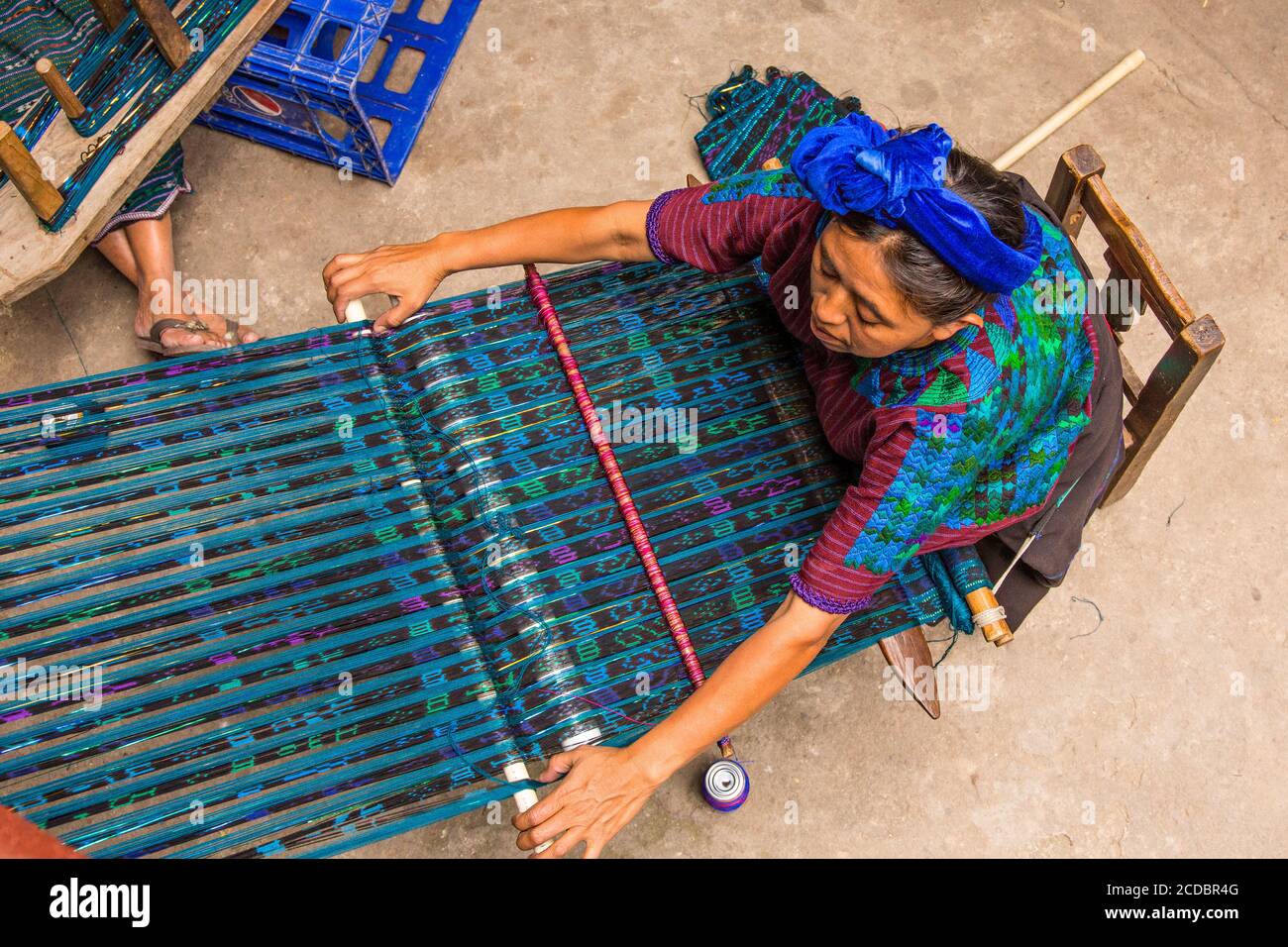A Mayan woman in traditional dress weaves fabric on a back loom in ...