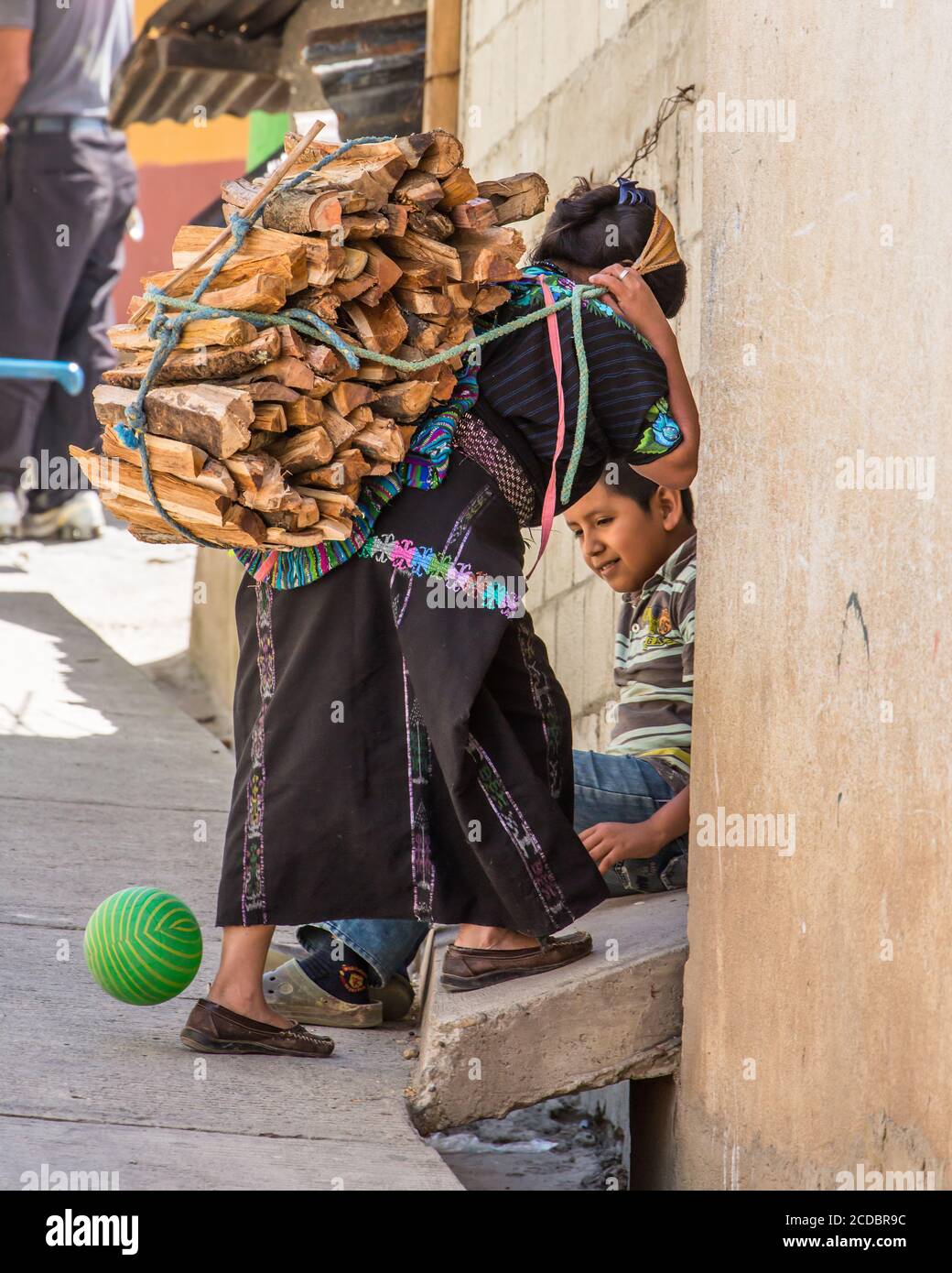 A Cakchiquel Mayan woman in traditional dress carries firewood on her ...