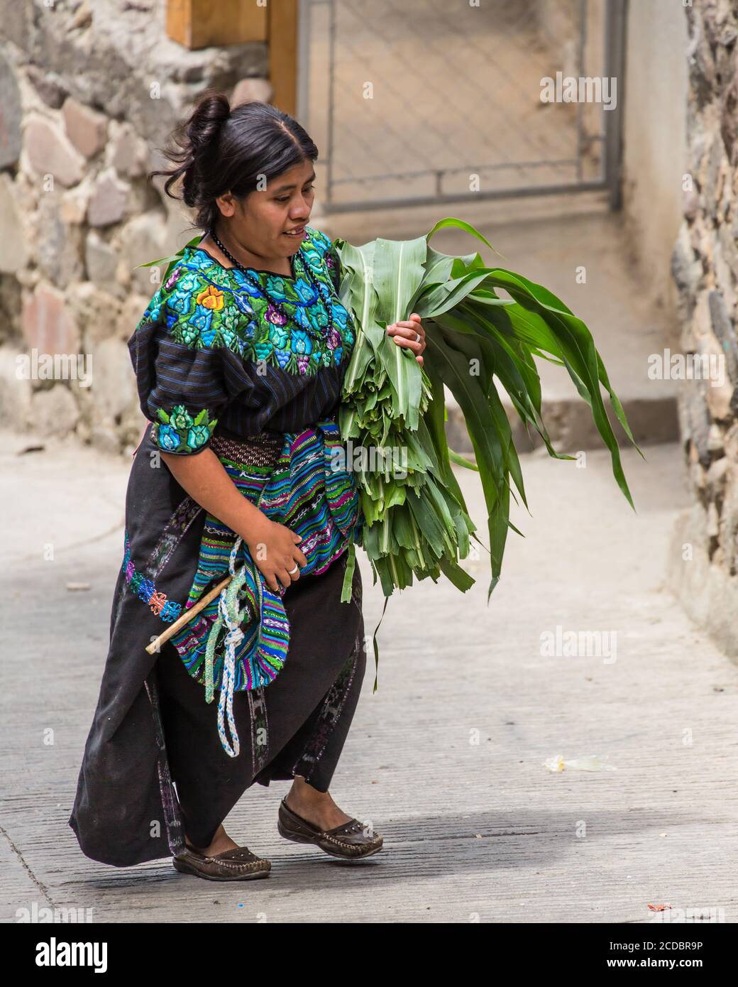 A Cakchiquel Mayan girl wearing traditional dress walks up the ...