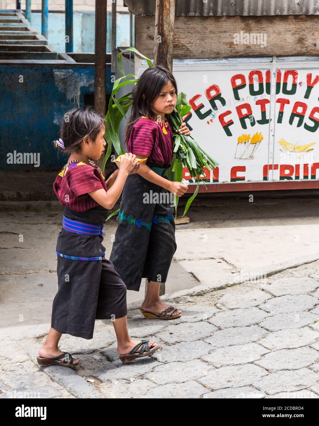Two young Cakchiquel Mayan girls wearing traditional dress wall up the ...