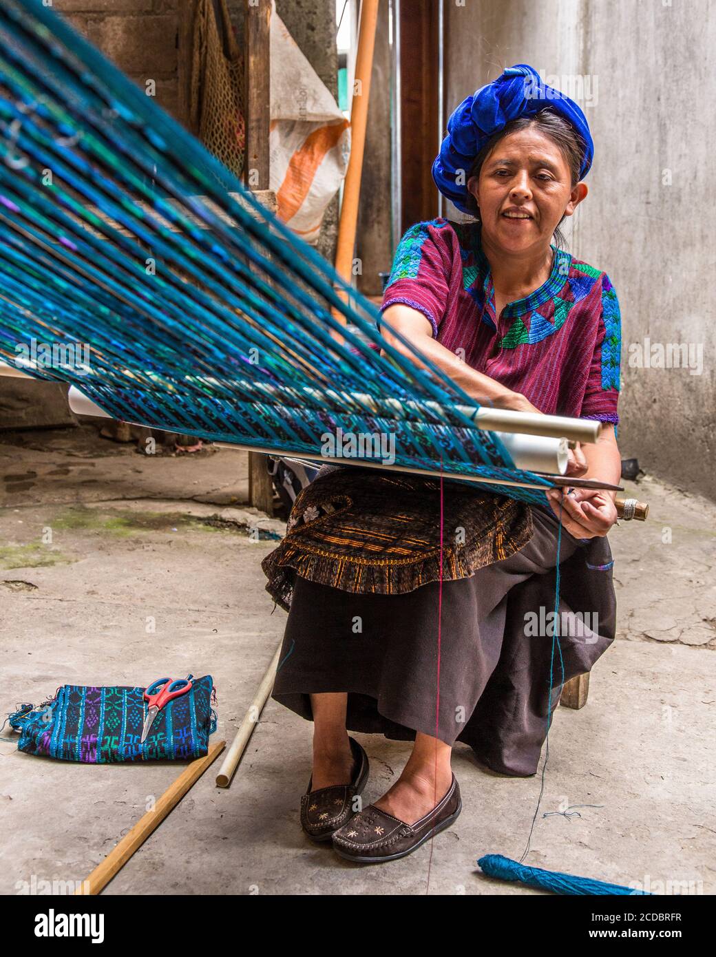 A Mayan woman in traditional dress weaves fabric on a back loom in ...
