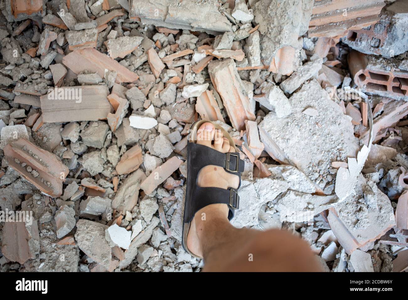 male feet in sandals over pile of building trash Stock Photo - Alamy