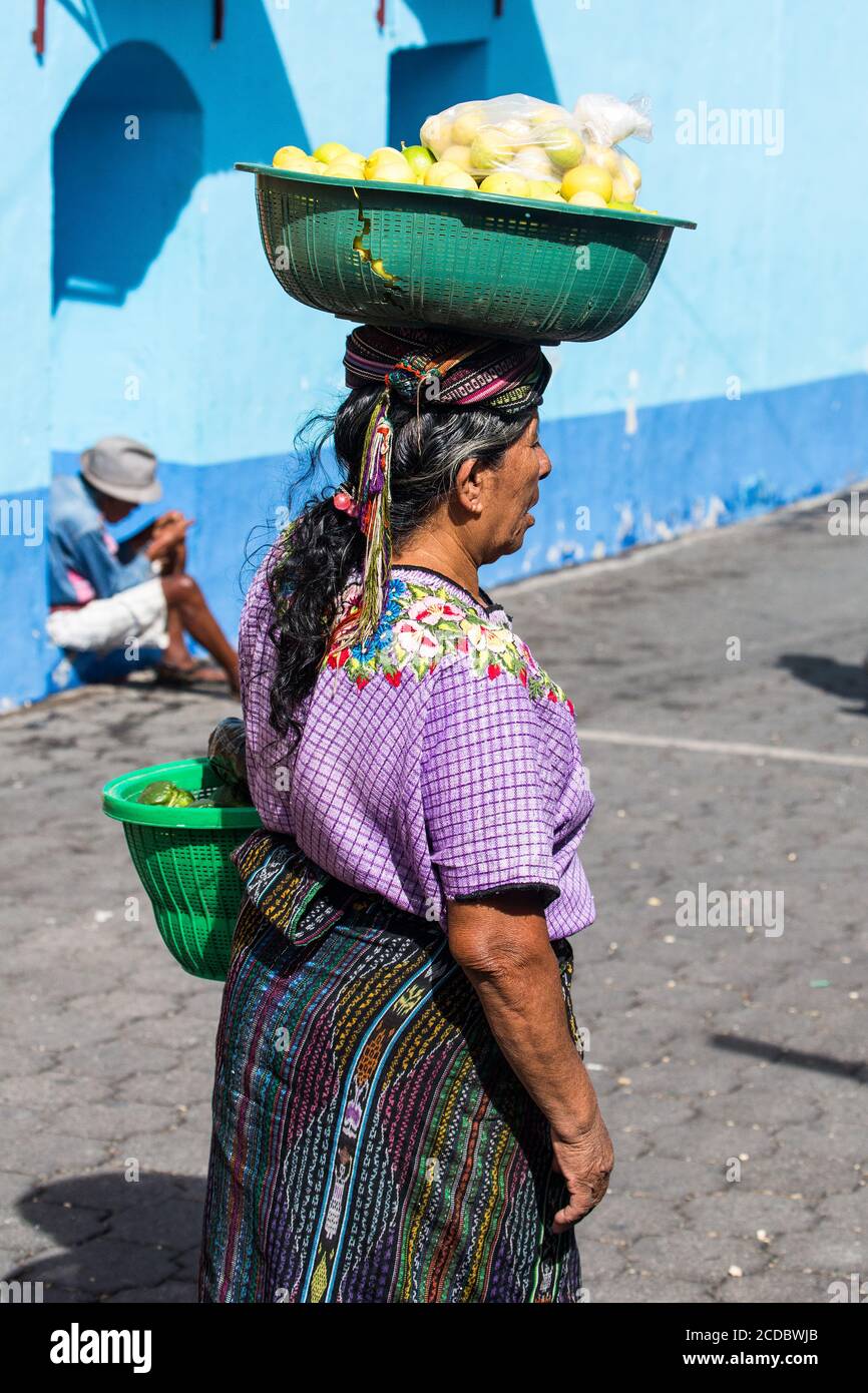 A Mayan woman wearing traditional dress balances a basket of lemons on ...