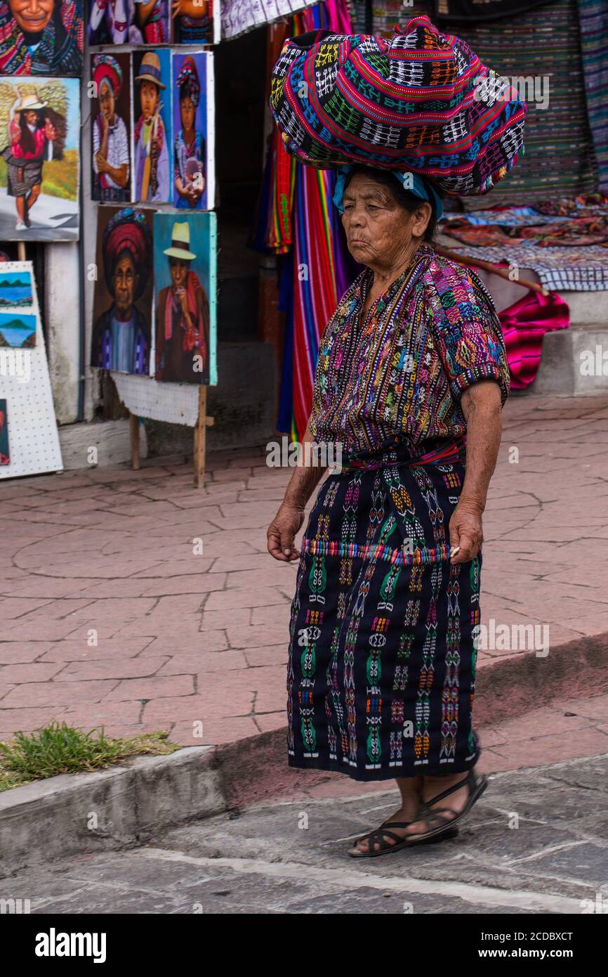 An older Tzutujil Mayan woman in traditional dress walks on a street in ...