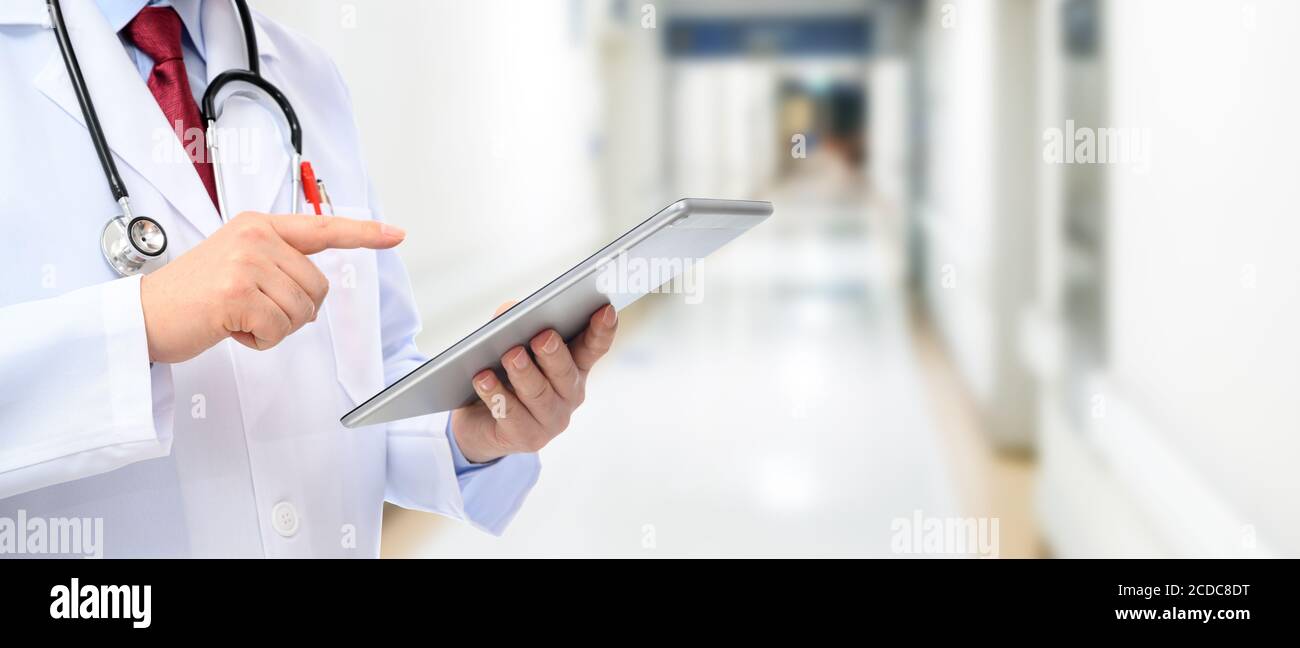 A side view of a male doctor using a tablet at the hospital Stock Photo ...