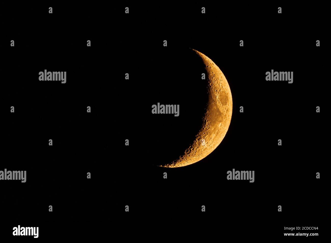 Orange colored waxing crescent moon; the orange glow is the result of ...