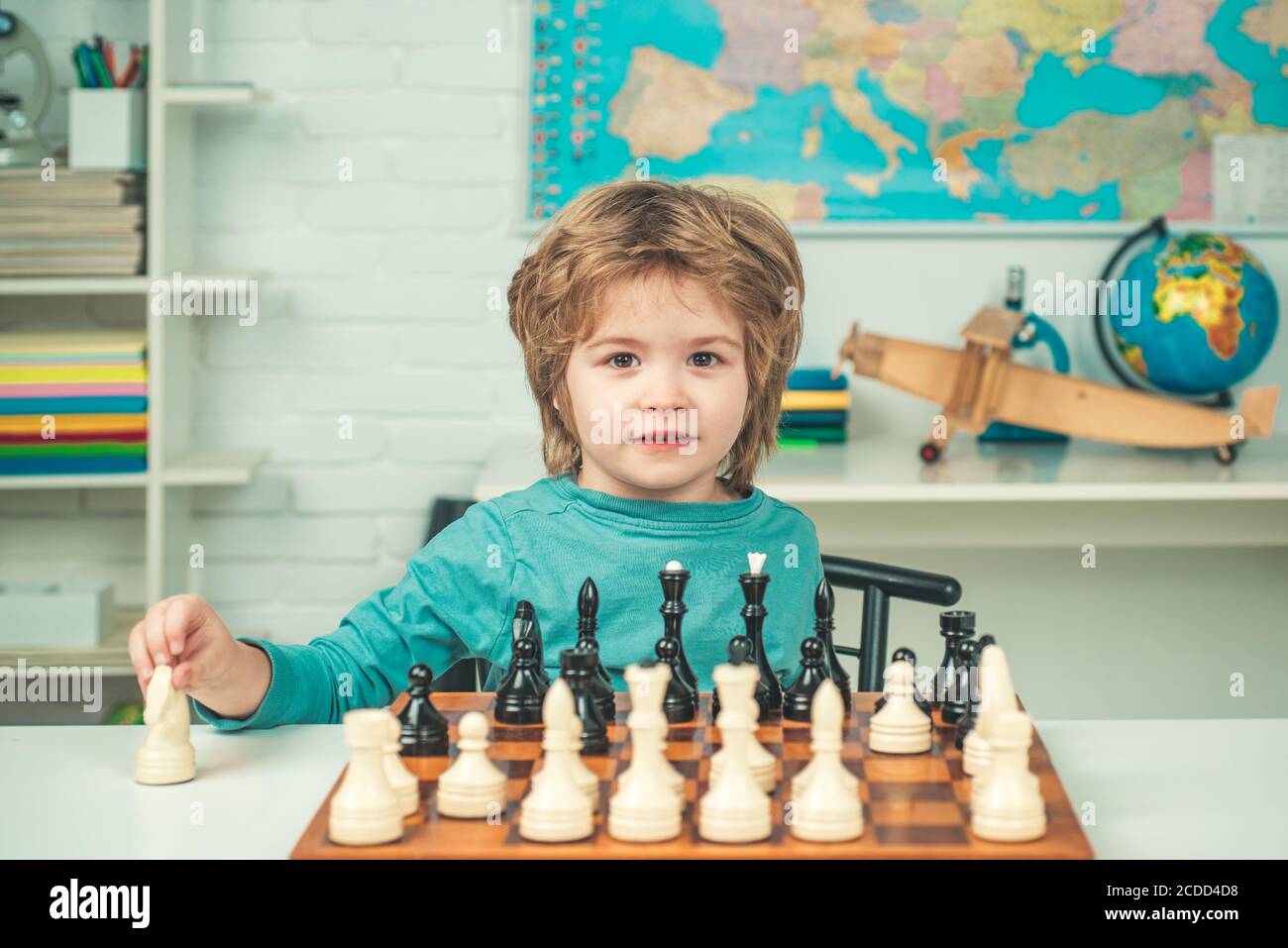 Chess school. Pupil kid thinking about his next move in a game of chess ...