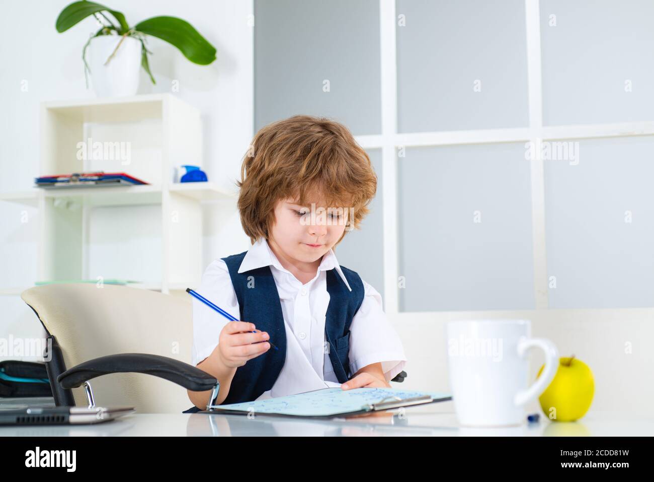 Little kid boy businessman making notes on the documents. Boring job ...