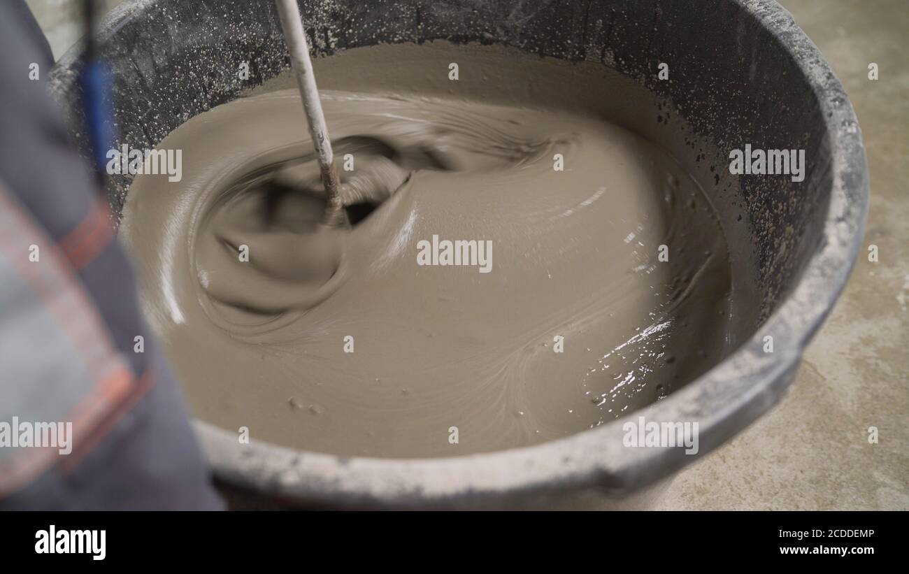 Mixing plaster solution in a bucket using electric drill. Construction ...