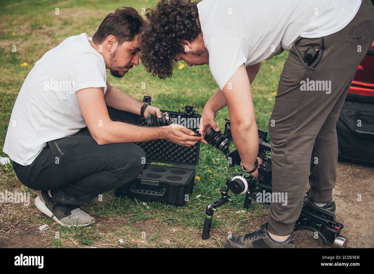 Behind the scene. Cameraman and assistant changes the lens on camera ...