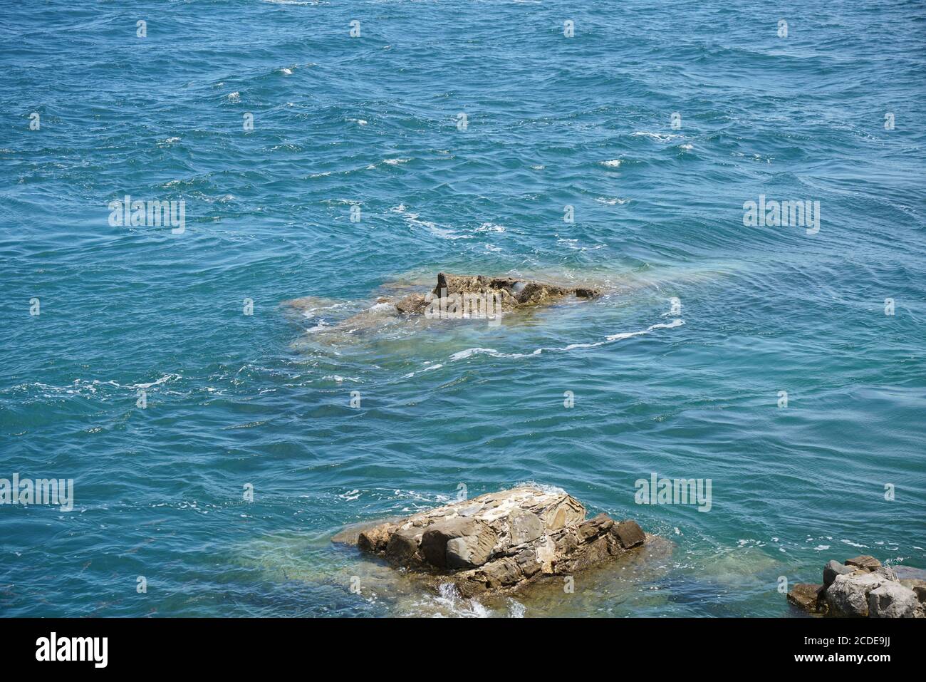Stones in the shallow blue water during the daytime Stock Photo - Alamy