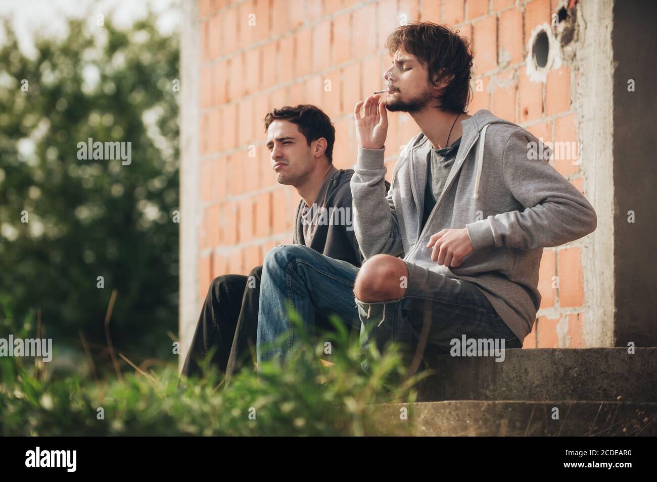Depressed and sad young man smoking cannabis or hashish joint with his ...