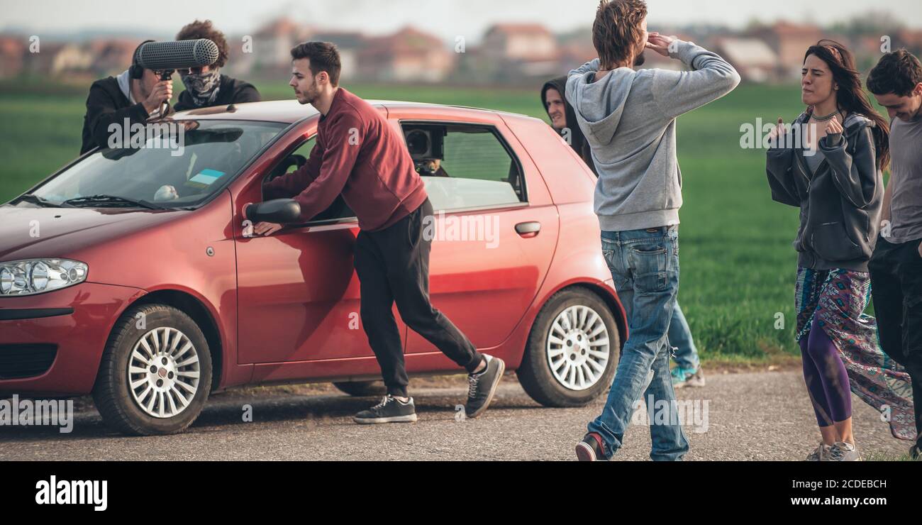 Behind scene improvisation. Film crew team pushing car while cameraman ...