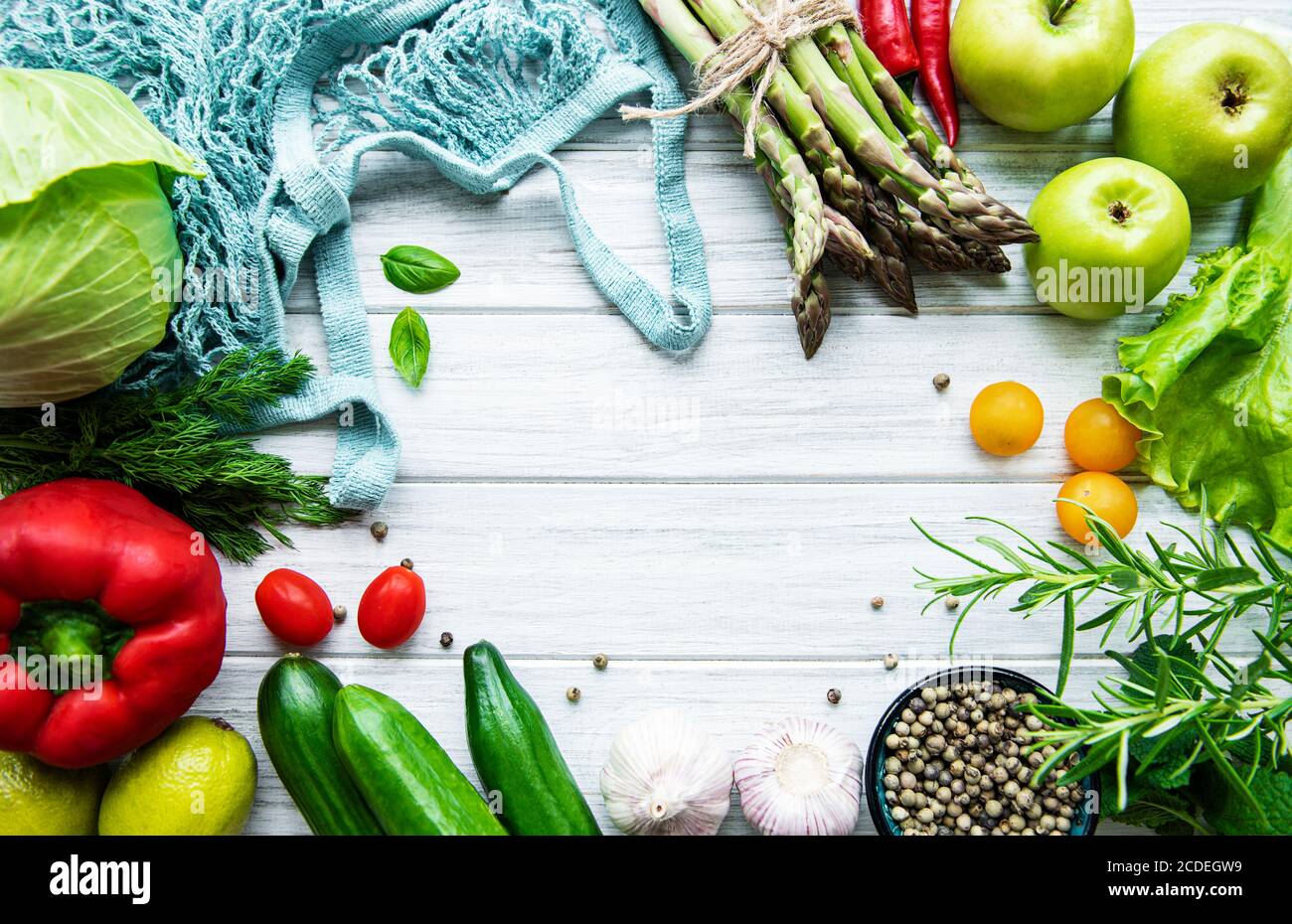 Fresh vegetables and fruits with a string bag on a white wooden ...