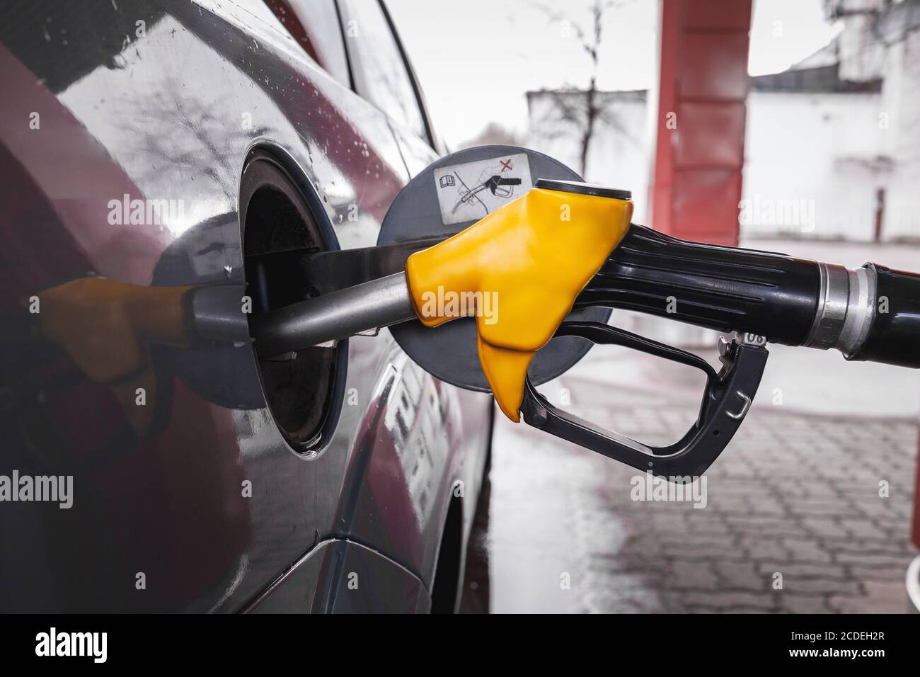 The yellow filling gun is inserted into the hole of the car's gas tank ...