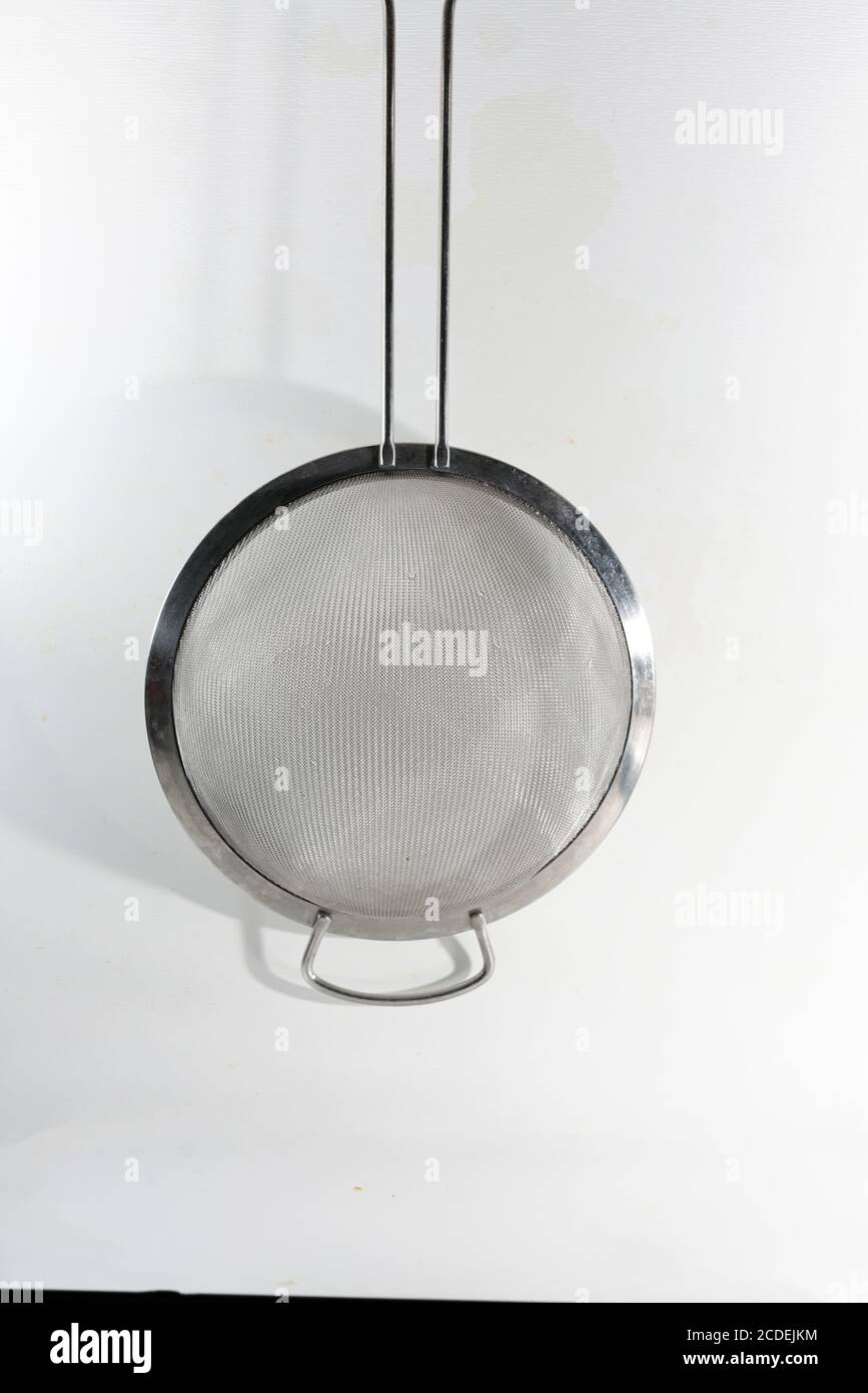 Silver mesh patterned strainer hanging from the wall Stock Photo - Alamy