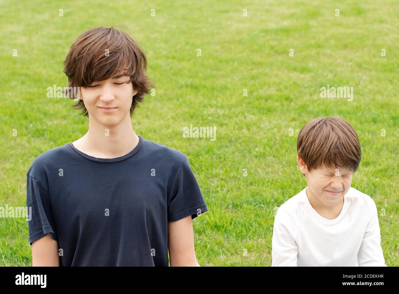 teenager and boy squint with closed eyes and a grin on his face. Green ...