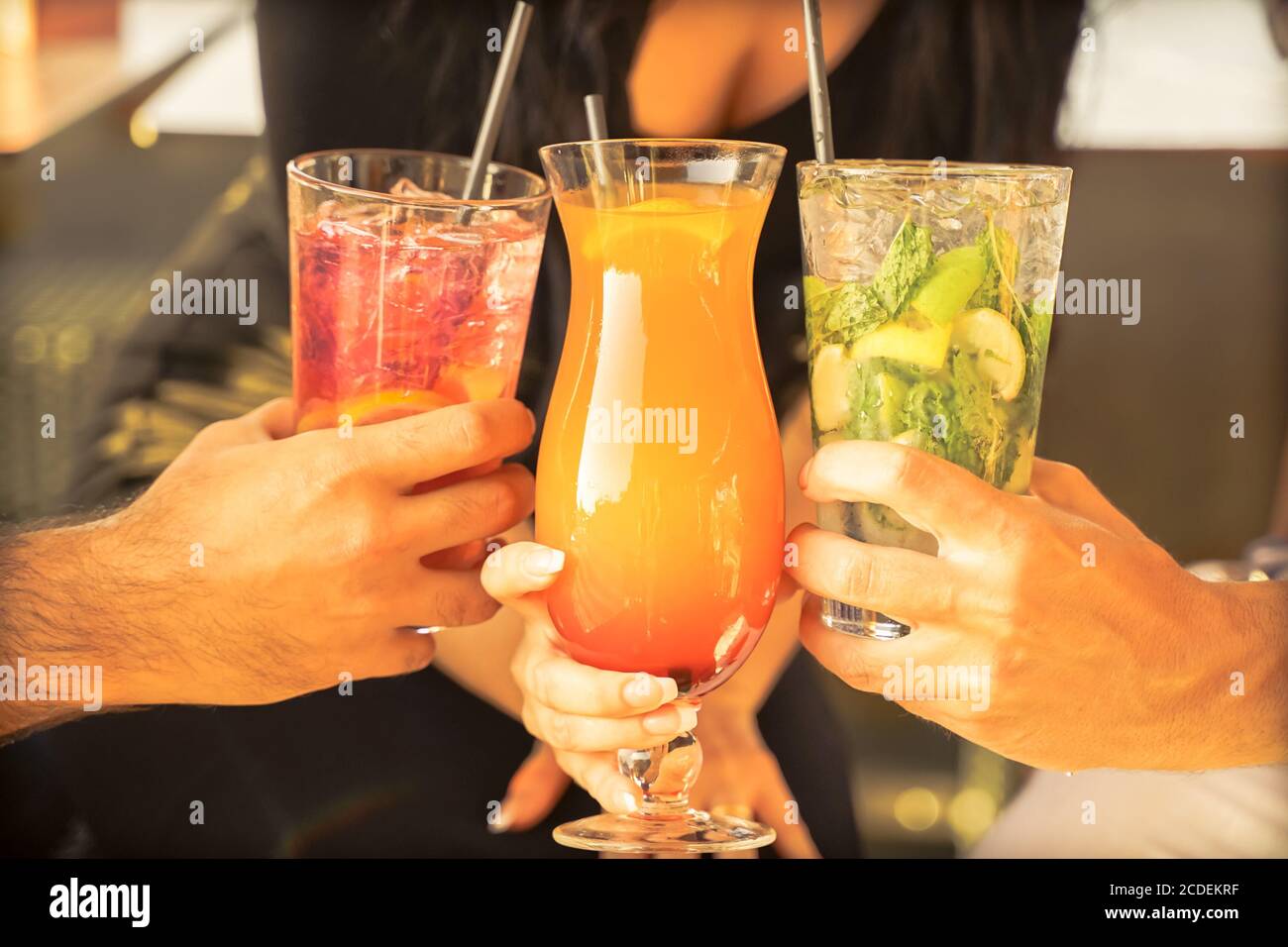 Hands with tropical cocktails at party. Young people drinking cocktails ...
