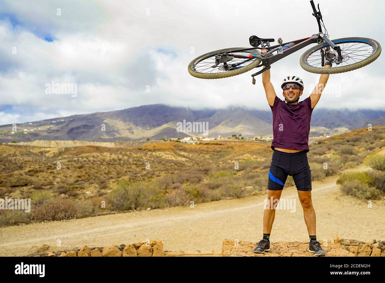 Happy male professional athlete cycling raising arms lifting bike ...