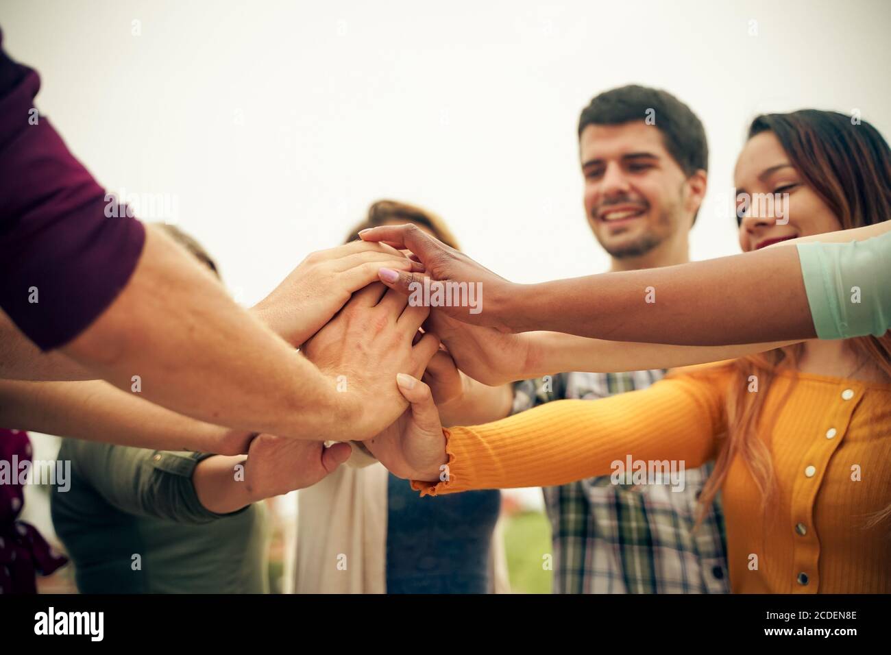 Young students putting their hands together. Friends with stack of ...