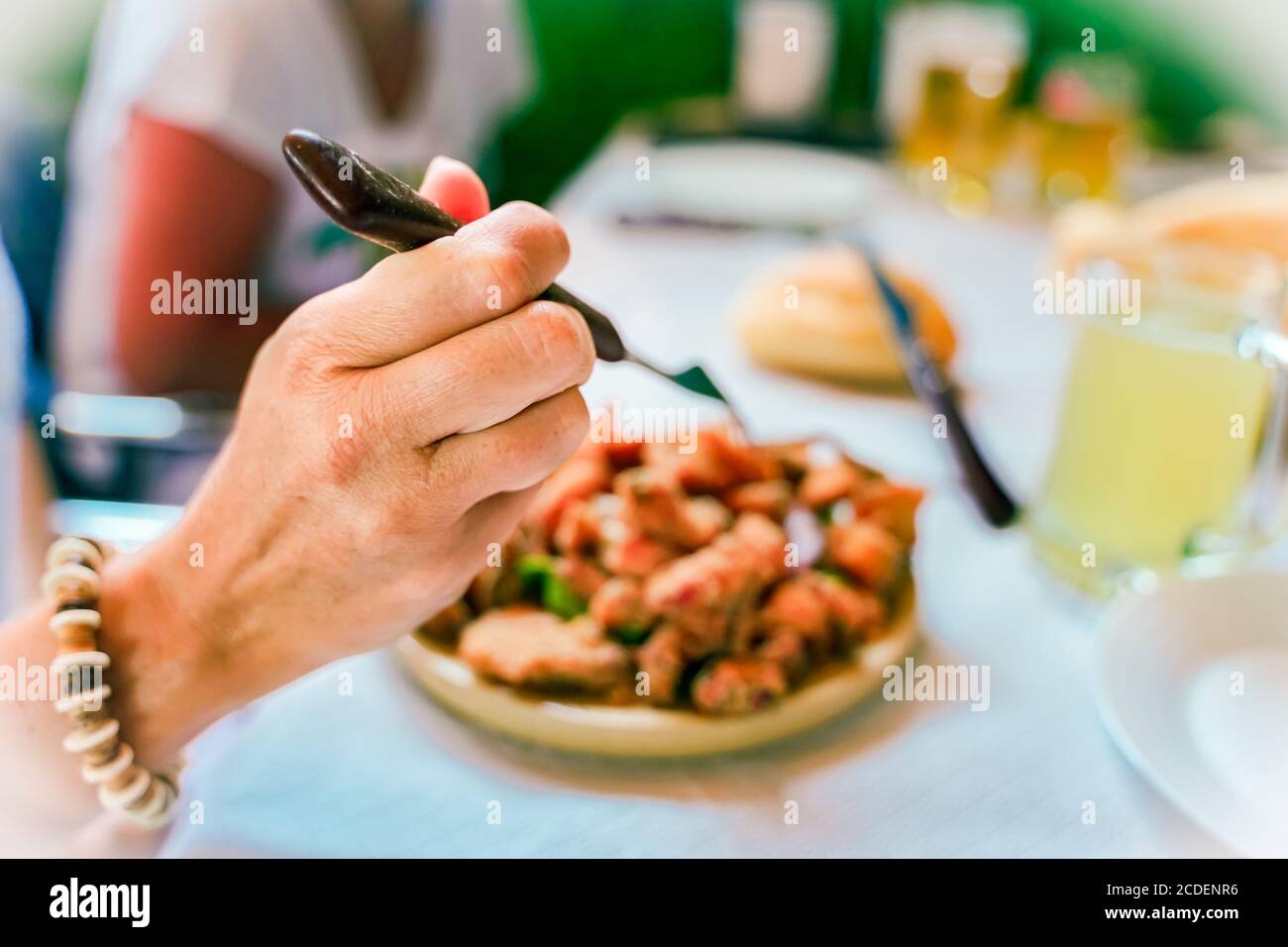 Hand holding a fork. A female hand is trying to use fork to eat. Focus ...
