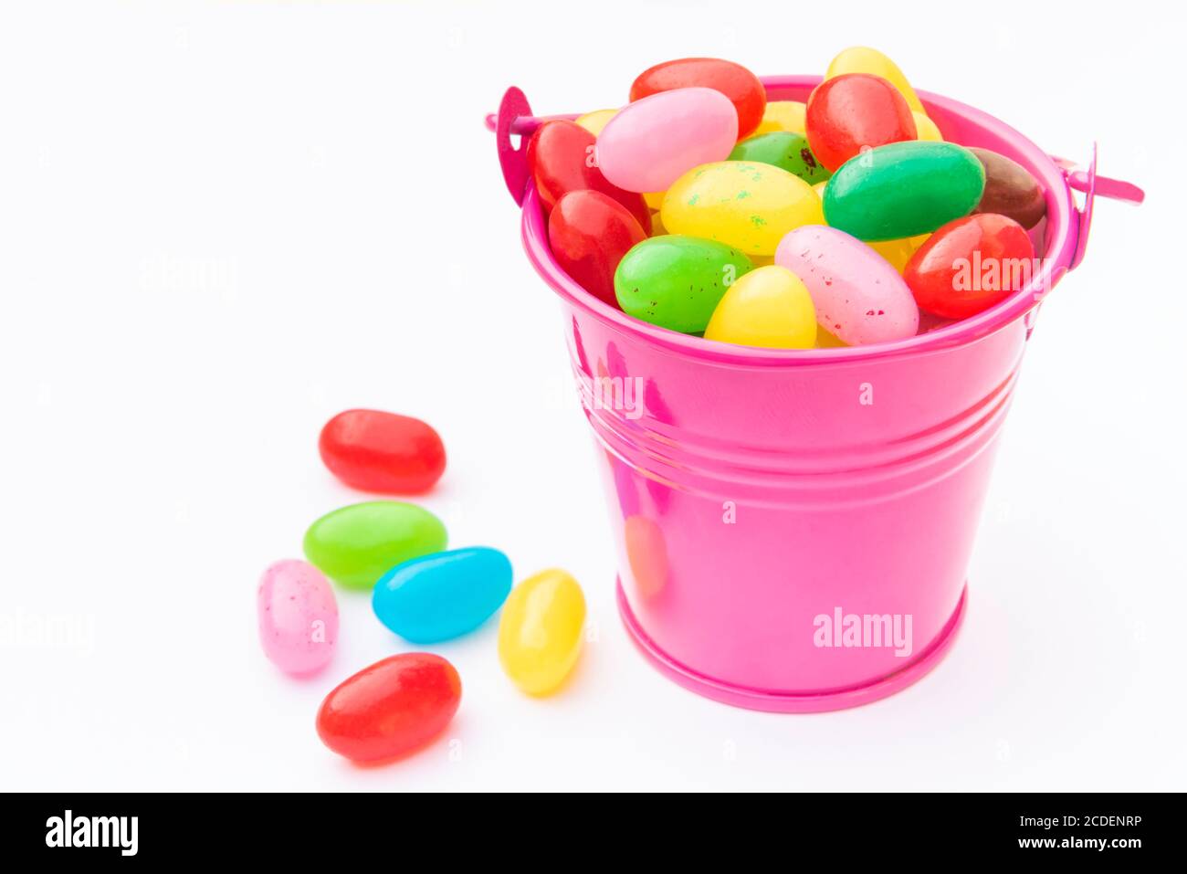 Colorful candies in pink bucket on a white background and near the ...