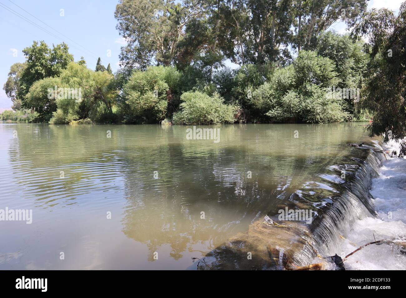 Dam and waterfall and shrubs in the Jordan River near Kibbutz Kfar Blum ...