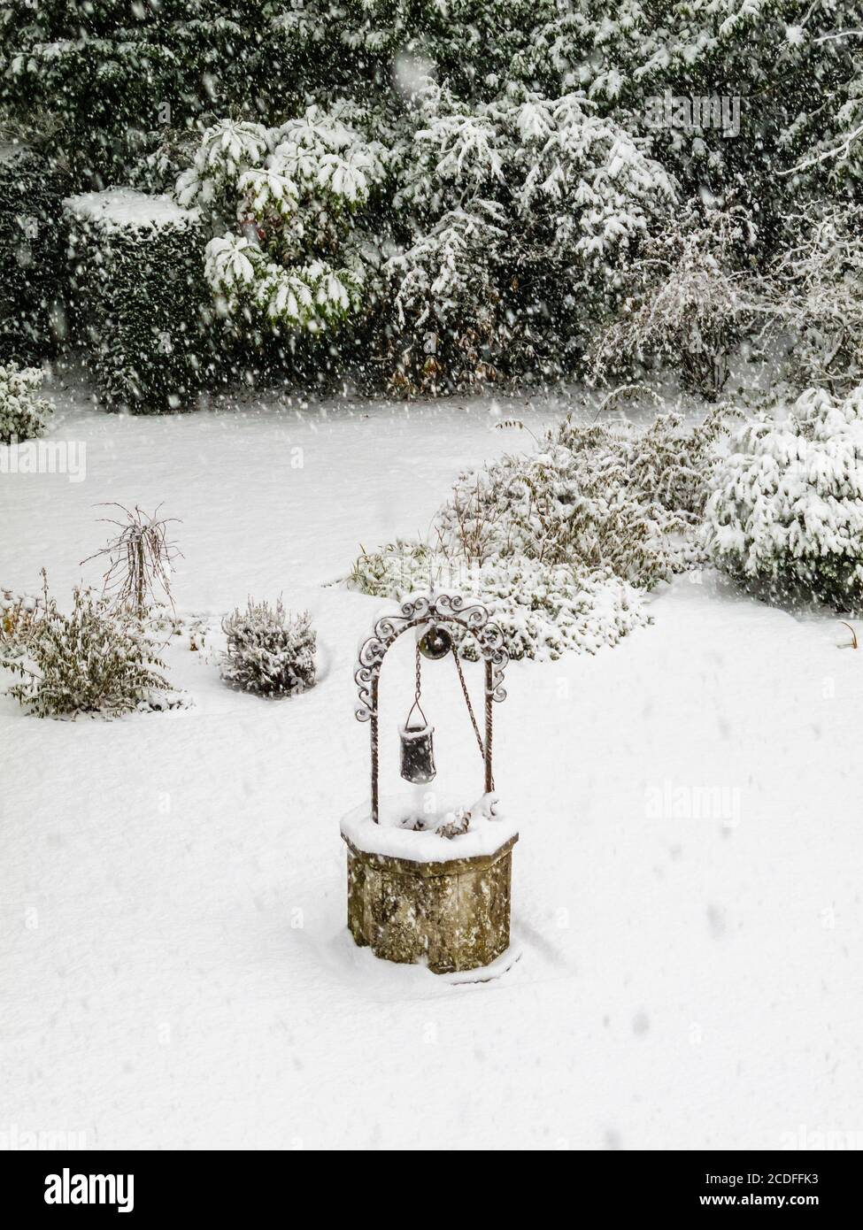 An ornamental well in front of snow covered trees in a large urban ...