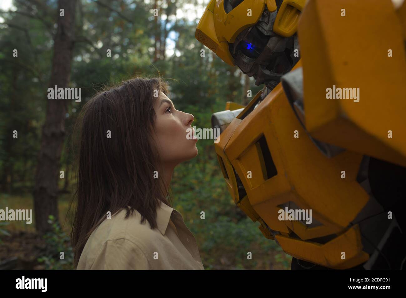 Portrait of a robot transformer and girl standing together among forest ...
