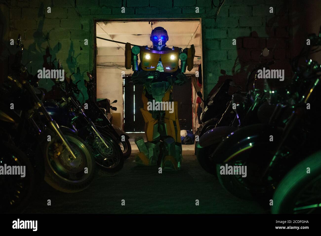 Cosplayer in image of a robot transformer stands among garage and glows ...