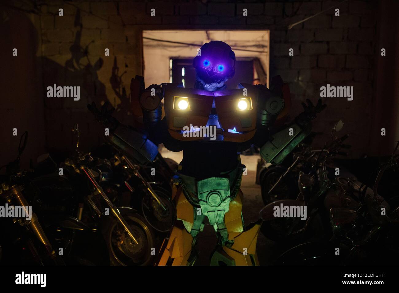 Cosplayer in image of a robot transformer stands among garage and glows ...