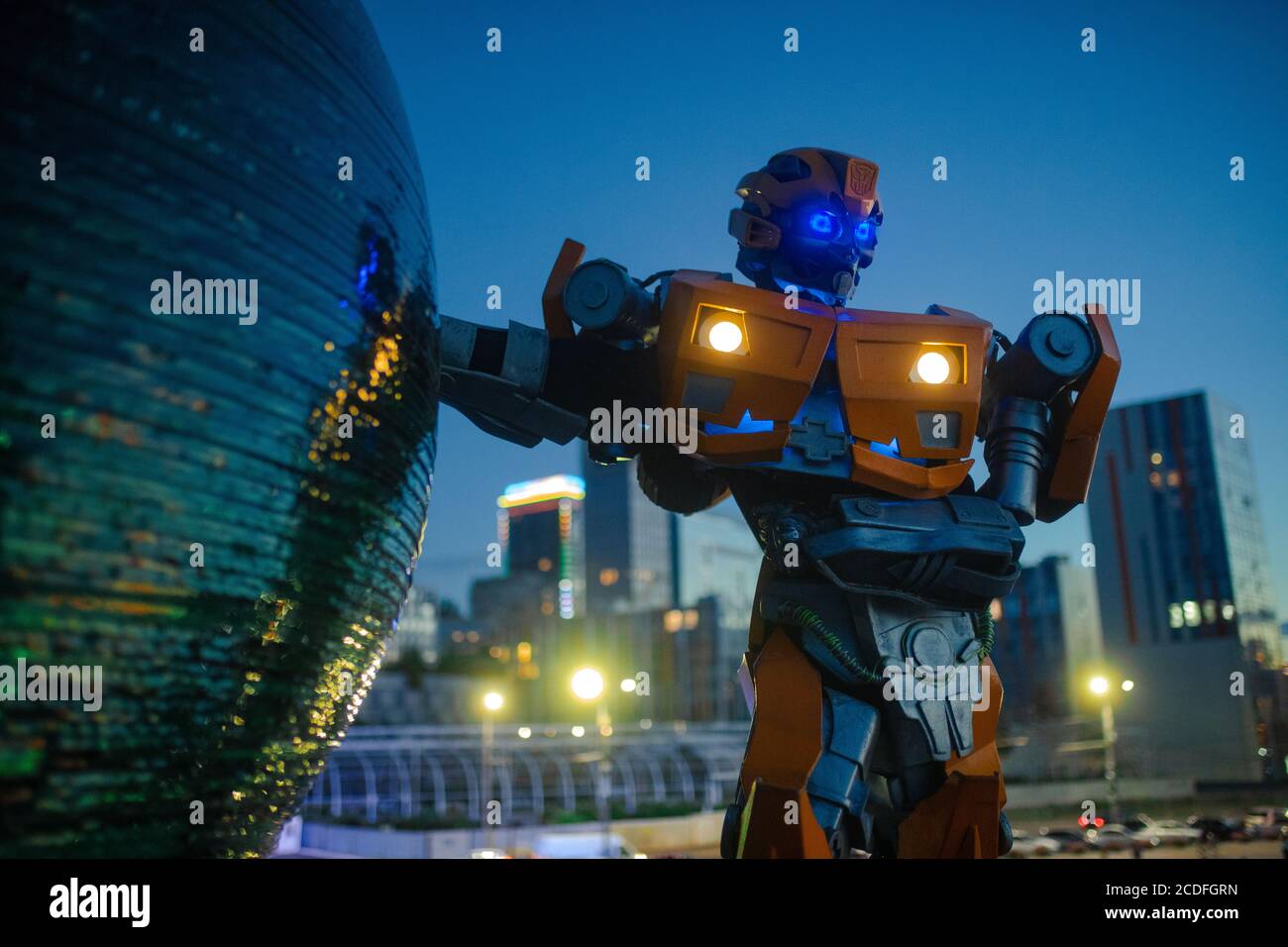 Robot transformer stands in street and glows in dark against background ...