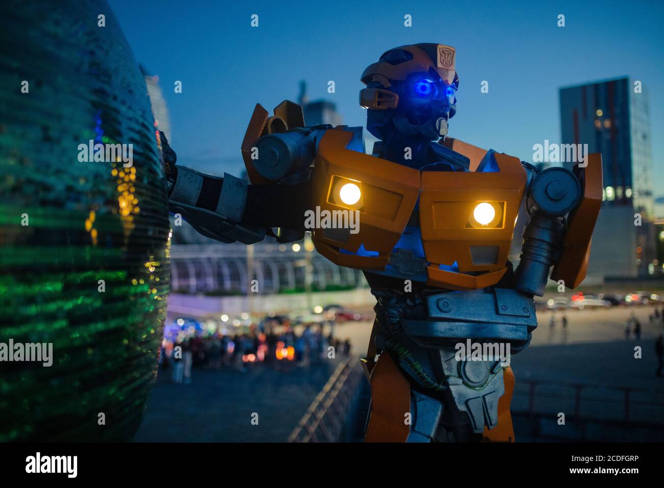 Robot transformer stands in street and glows in dark against background ...