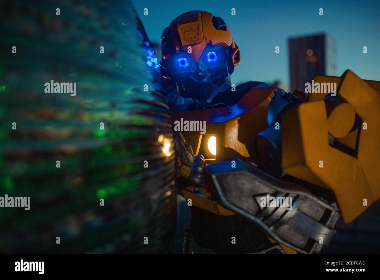 Robot transformer stands in street and glows in dark against background ...