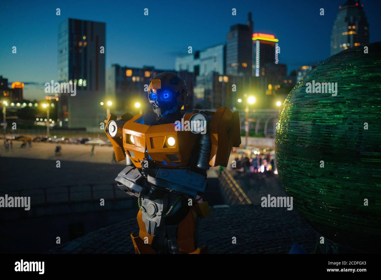 Robot transformer stands in street and glows in dark against background ...
