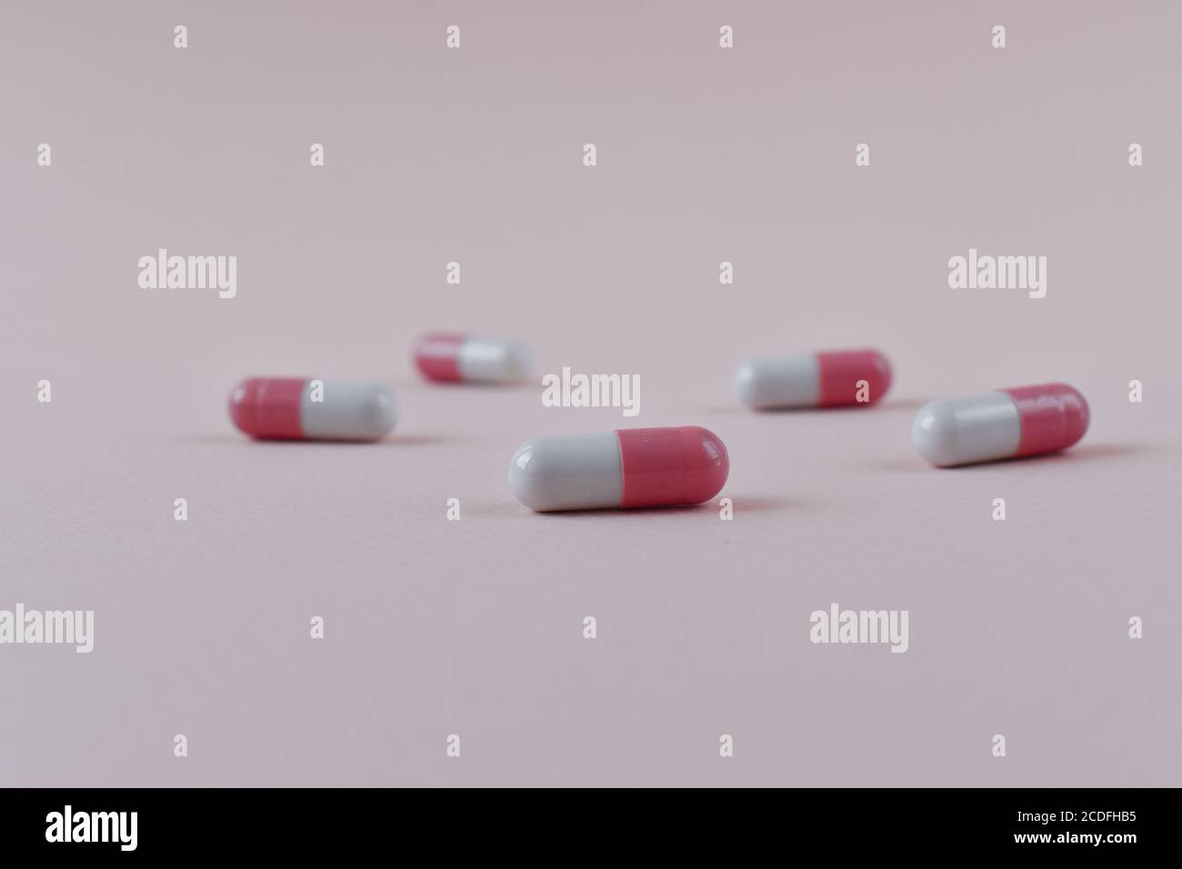 Pink capsules on a pink background. The tablets are insulated against a ...