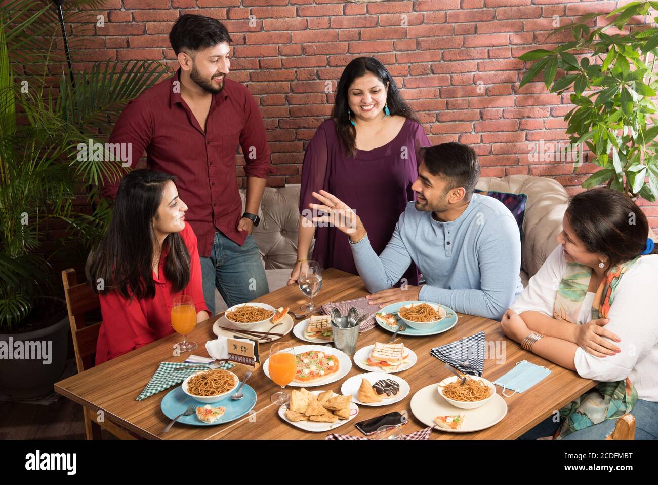 Indian friends eating or dining in restaurant. Asian people in face for ...
