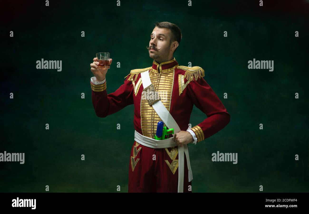 Royal whiskey. Young man in suit as Nicholas II isolated on dark green ...