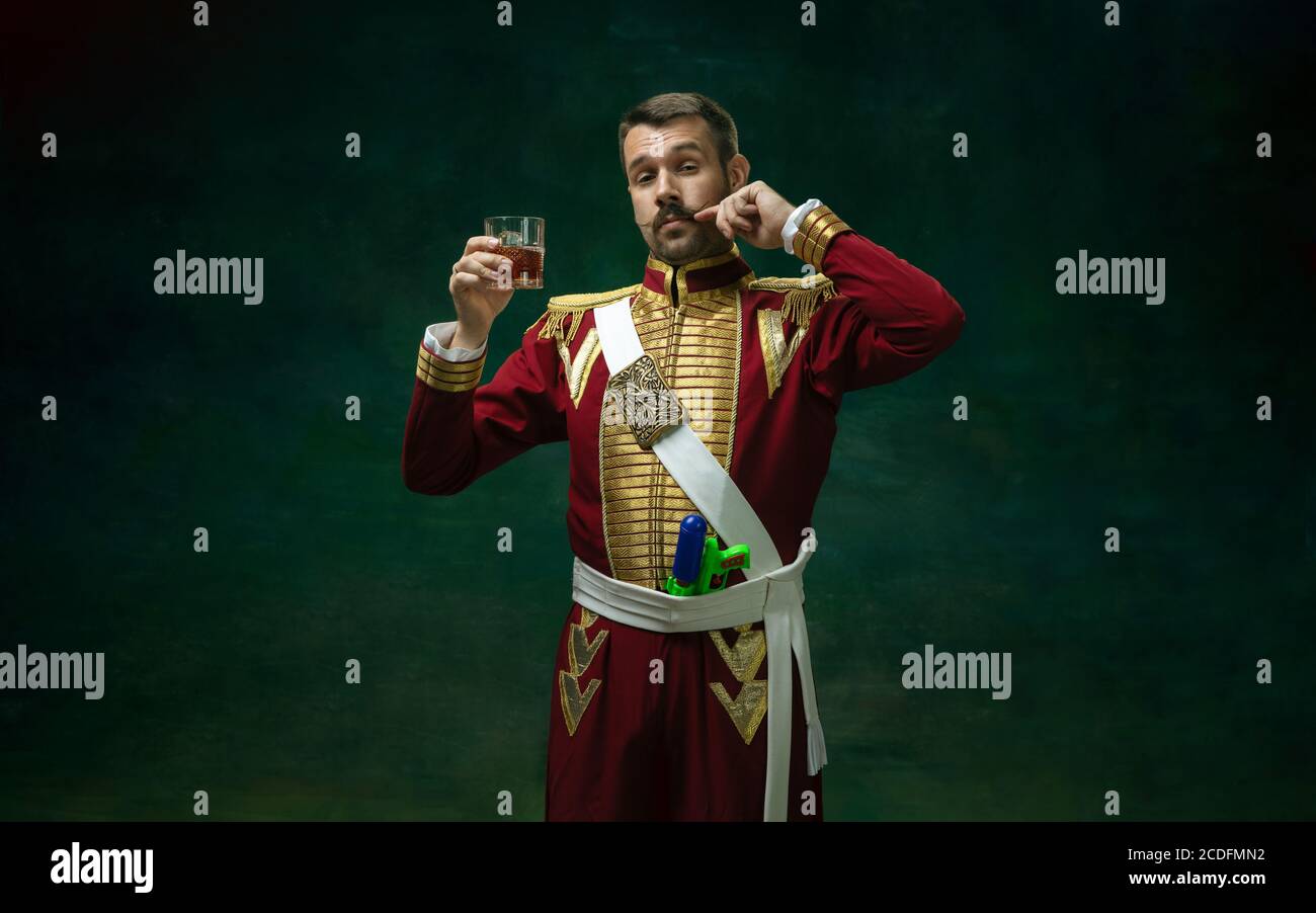 Royal whiskey. Young man in suit as Nicholas II isolated on dark green ...