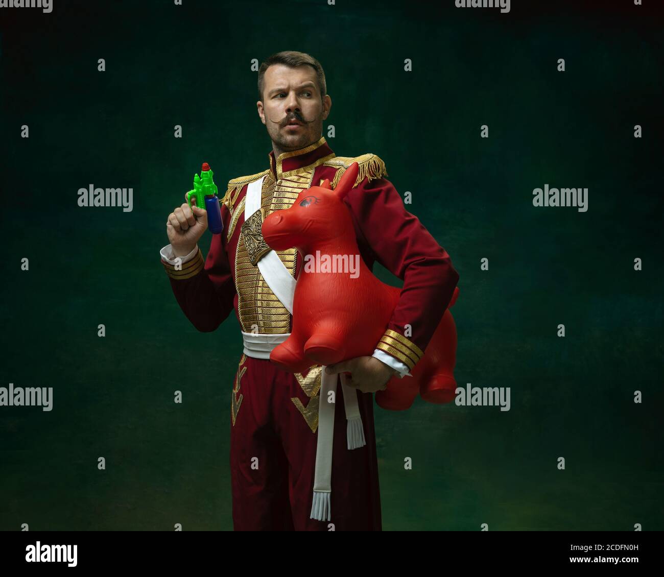 Faithful horse. Young man in suit as Nicholas II isolated on dark green ...