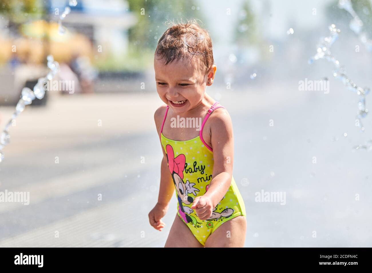 Cute baby playing in fountain. Little girl playing with waterspouts ...