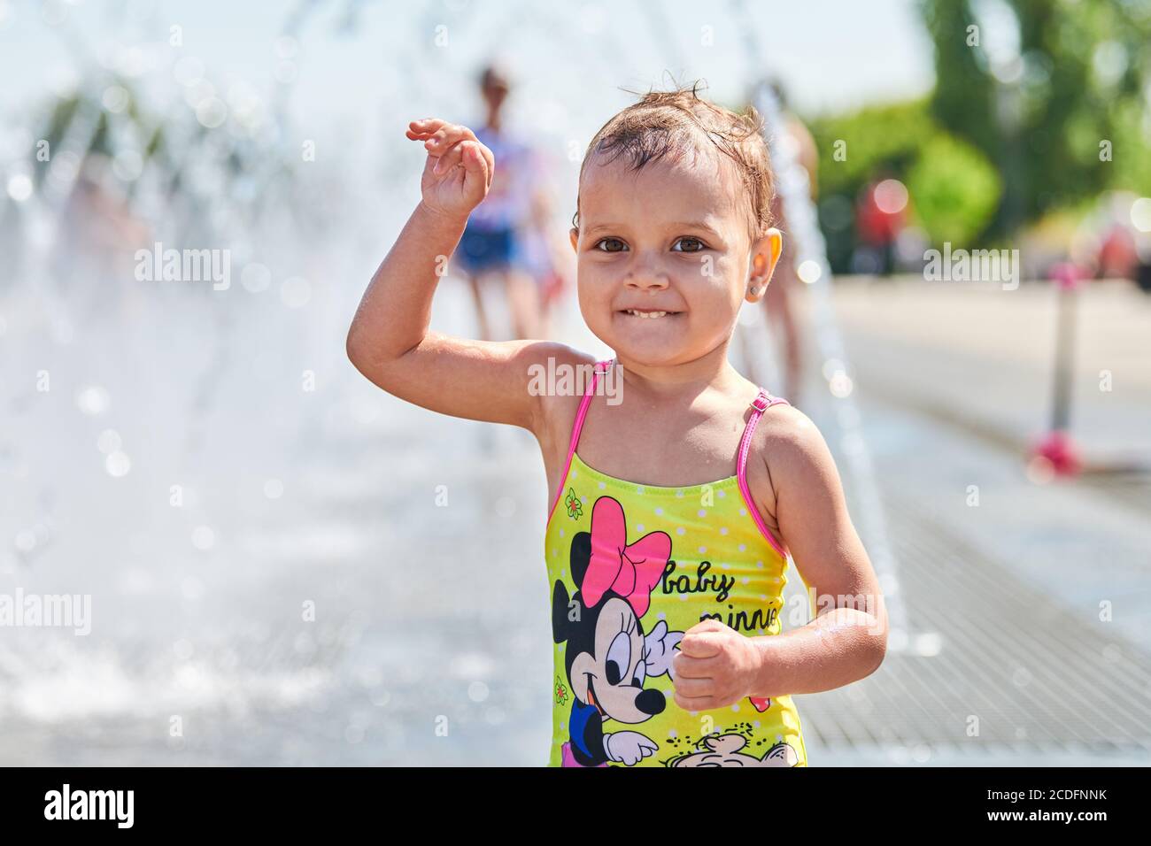 Cute baby playing in fountain. Little girl playing with waterspouts ...