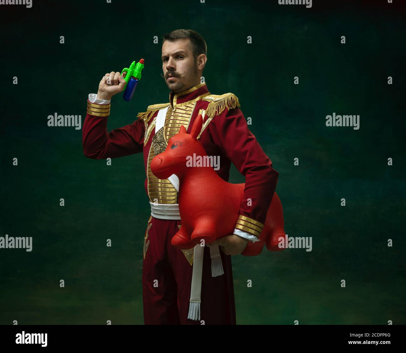 Faithful horse. Young man in suit as Nicholas II isolated on dark green ...